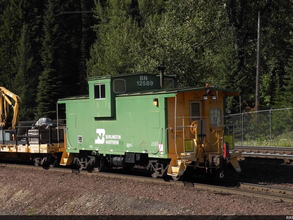 Very nice green BN caboose on the end of a tie laying train.